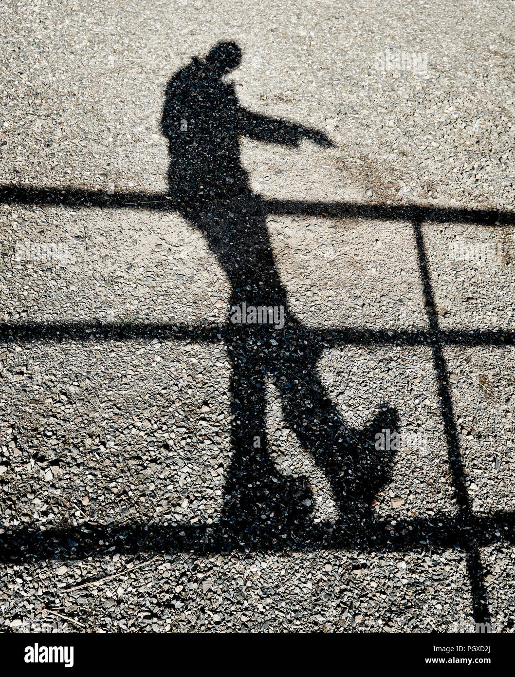 Shadow of a person balancing on one leg on a fence reflected on a ...