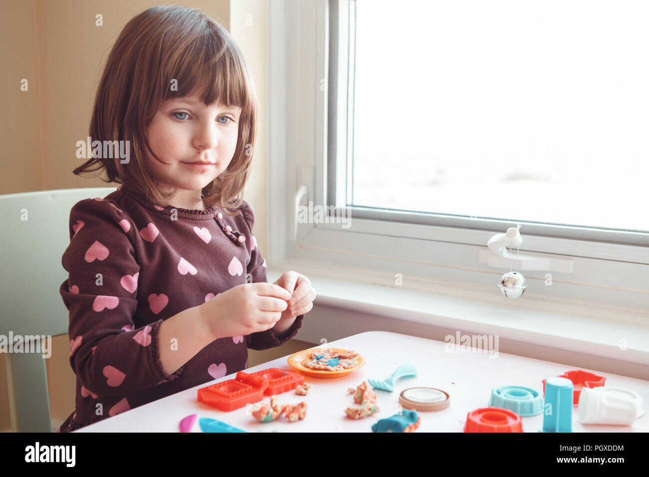 Portrait of cute white Caucasian preschooler girl playing plasticine ...