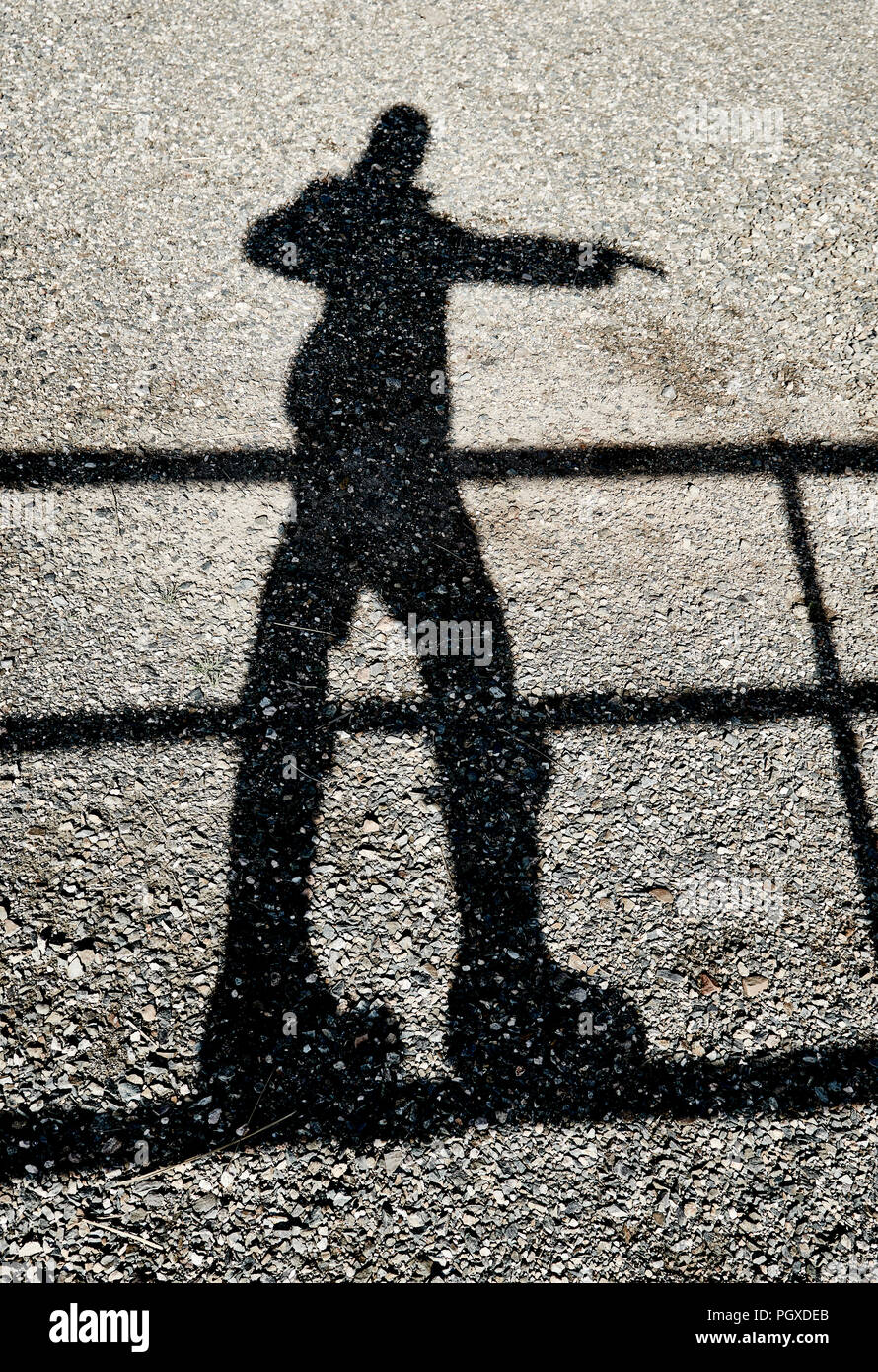 Shadow of a person balancing on a rail while bending over looking ...