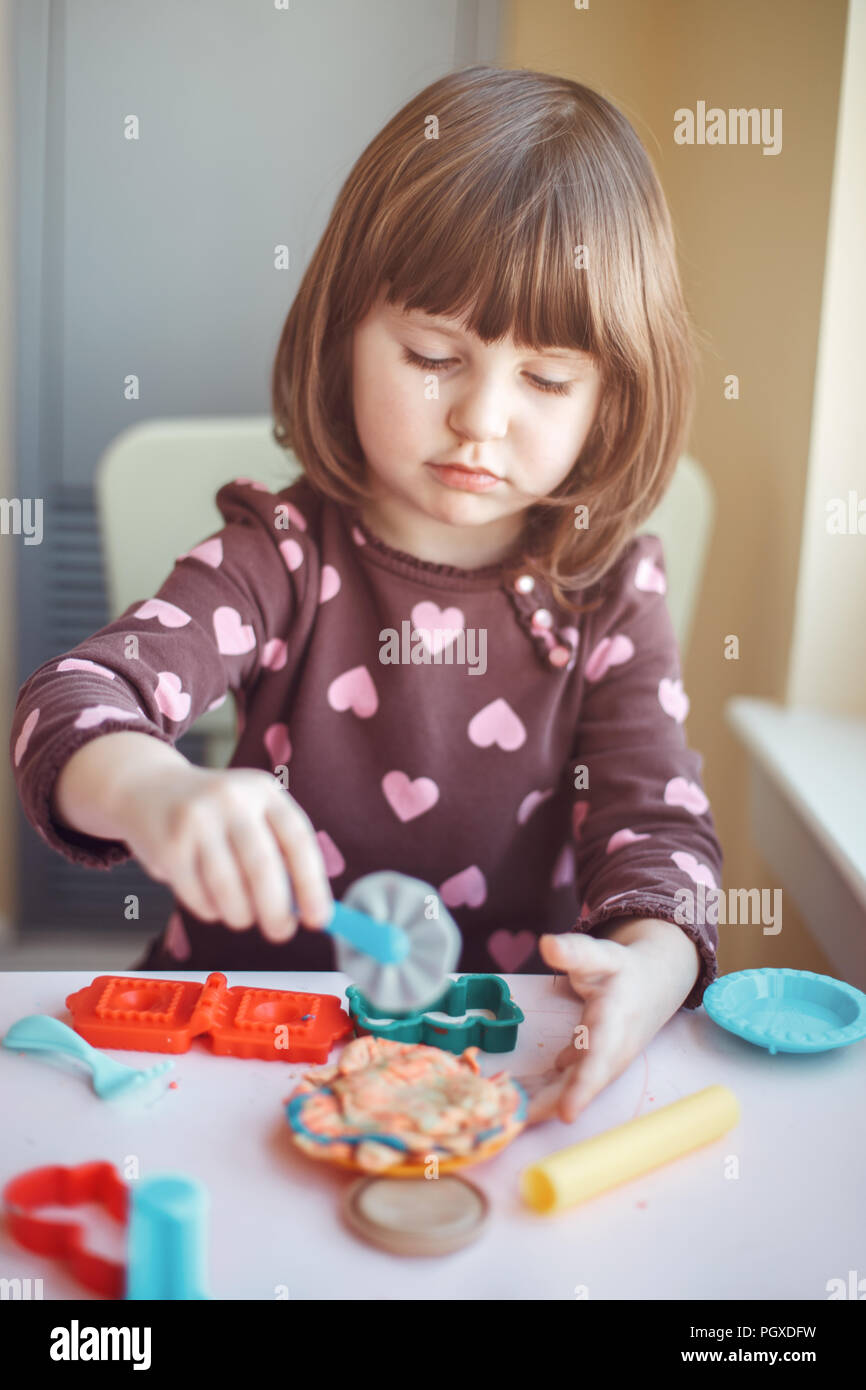 Portrait of cute white Caucasian preschooler girl playing plasticine ...