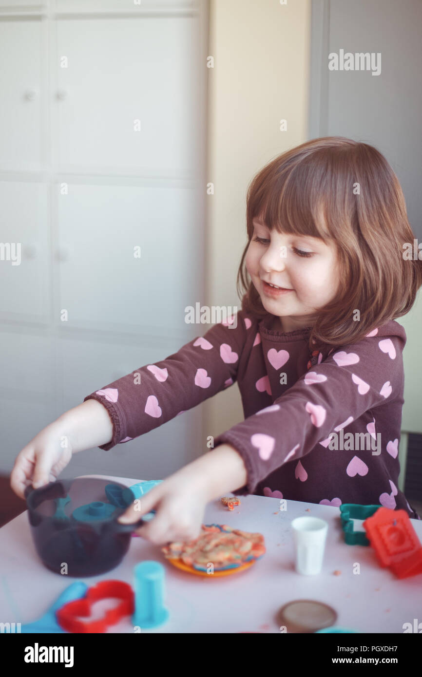 Portrait of cute white Caucasian preschooler girl playing plasticine ...
