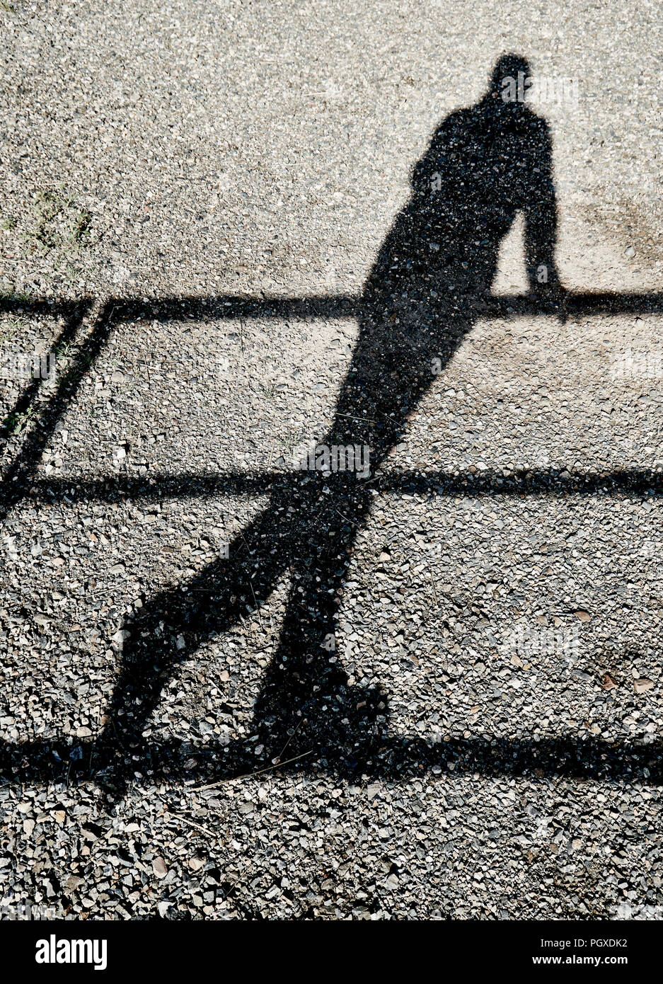Shadow of a person balancing on a rail while bending over looking ...
