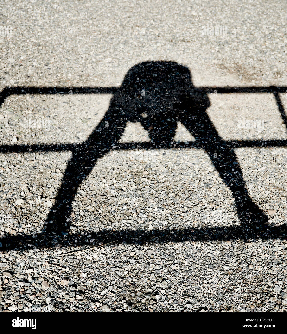 Shadow of a person balancing on a rail while bending over looking ...