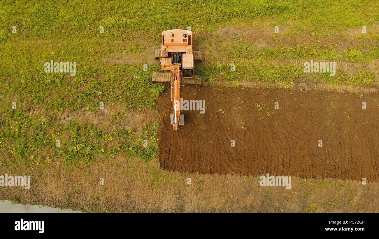 Excavator is digging an irrigation canal. Aerial view:Excavator digging ...