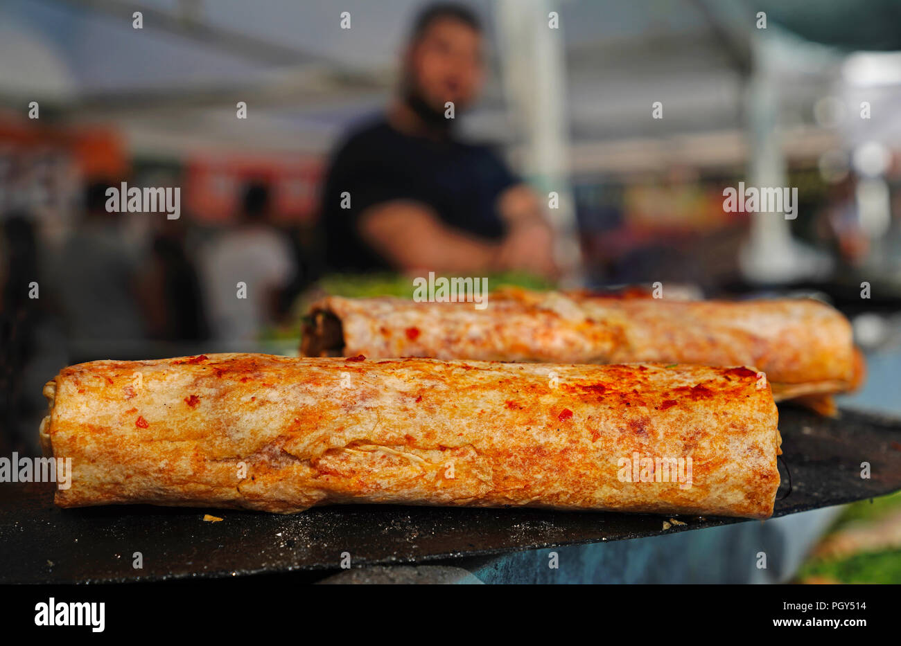 Hatay tavuk durum (chicken wrap), with a blurred customer in background ...