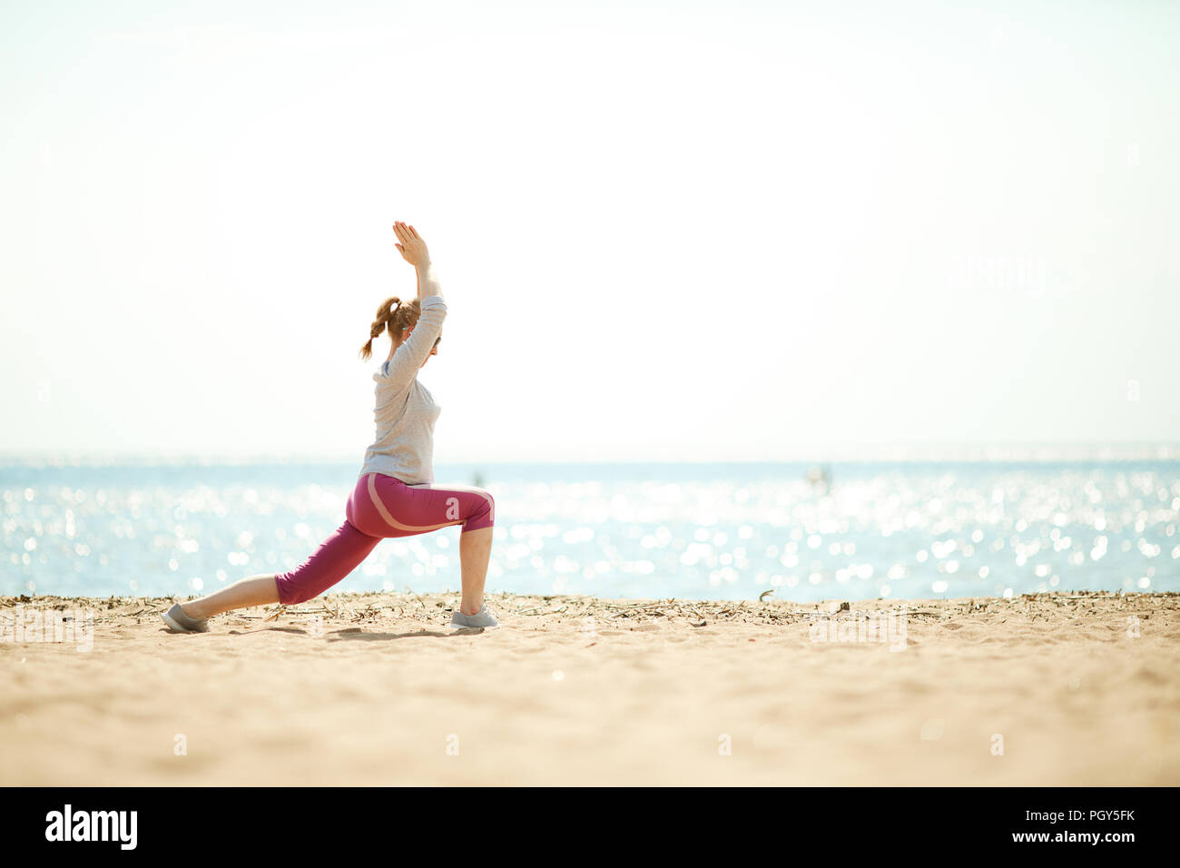 Side view of active female doing exercises for leg stretch and arms by ...