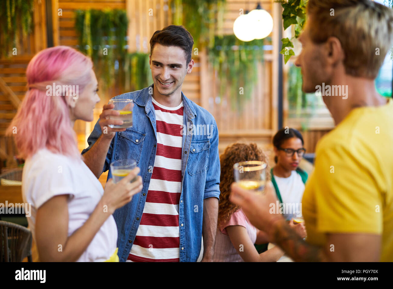 Two guys and girl cheering up with drinks and talking after dinner in ...