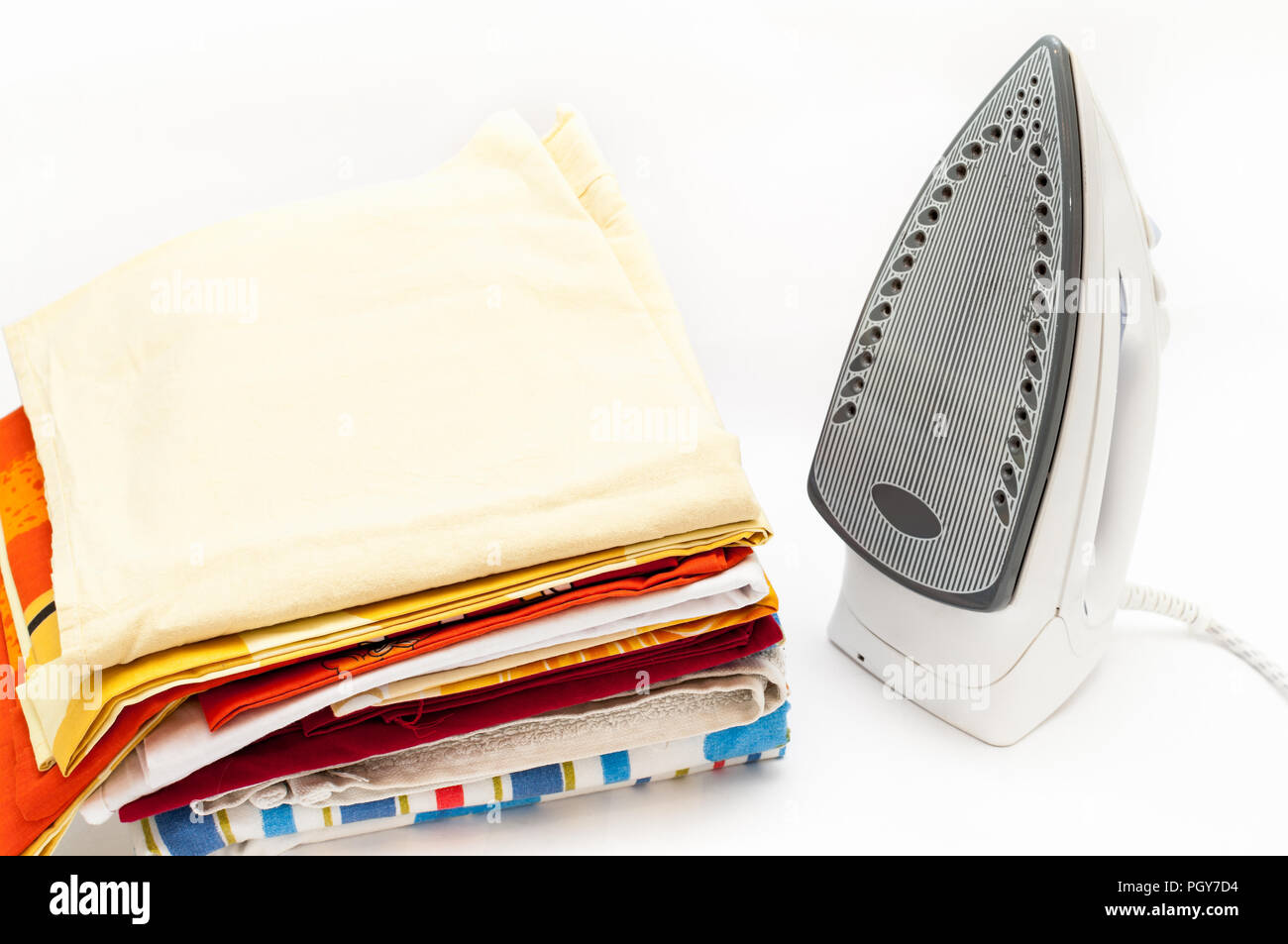 Pile of pressed colourful clothes and contemporary iron on isolated ...