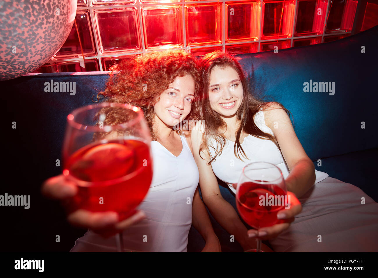 Two cheerful girls cheering up with homemade drinks while relaxing on ...