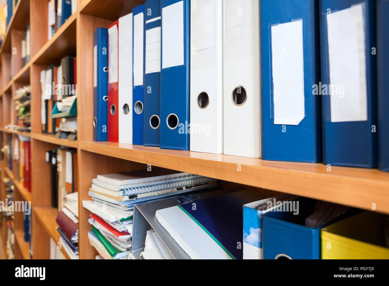 Perspective view at of colourful binders sorted on office shelves, an ...