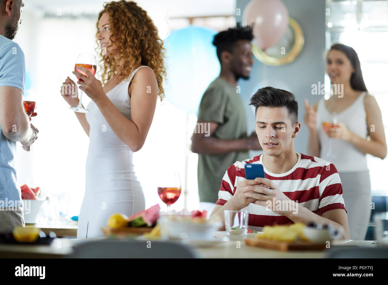 One of guys sitting by served table at party and messaging in ...