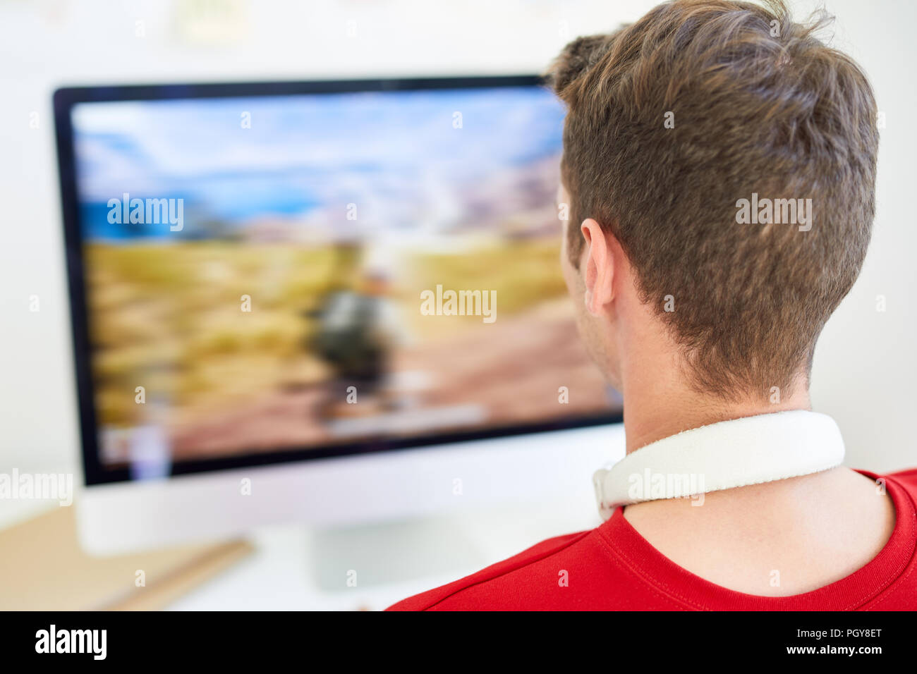 Rear view of footage editor looking through video on computer screen ...
