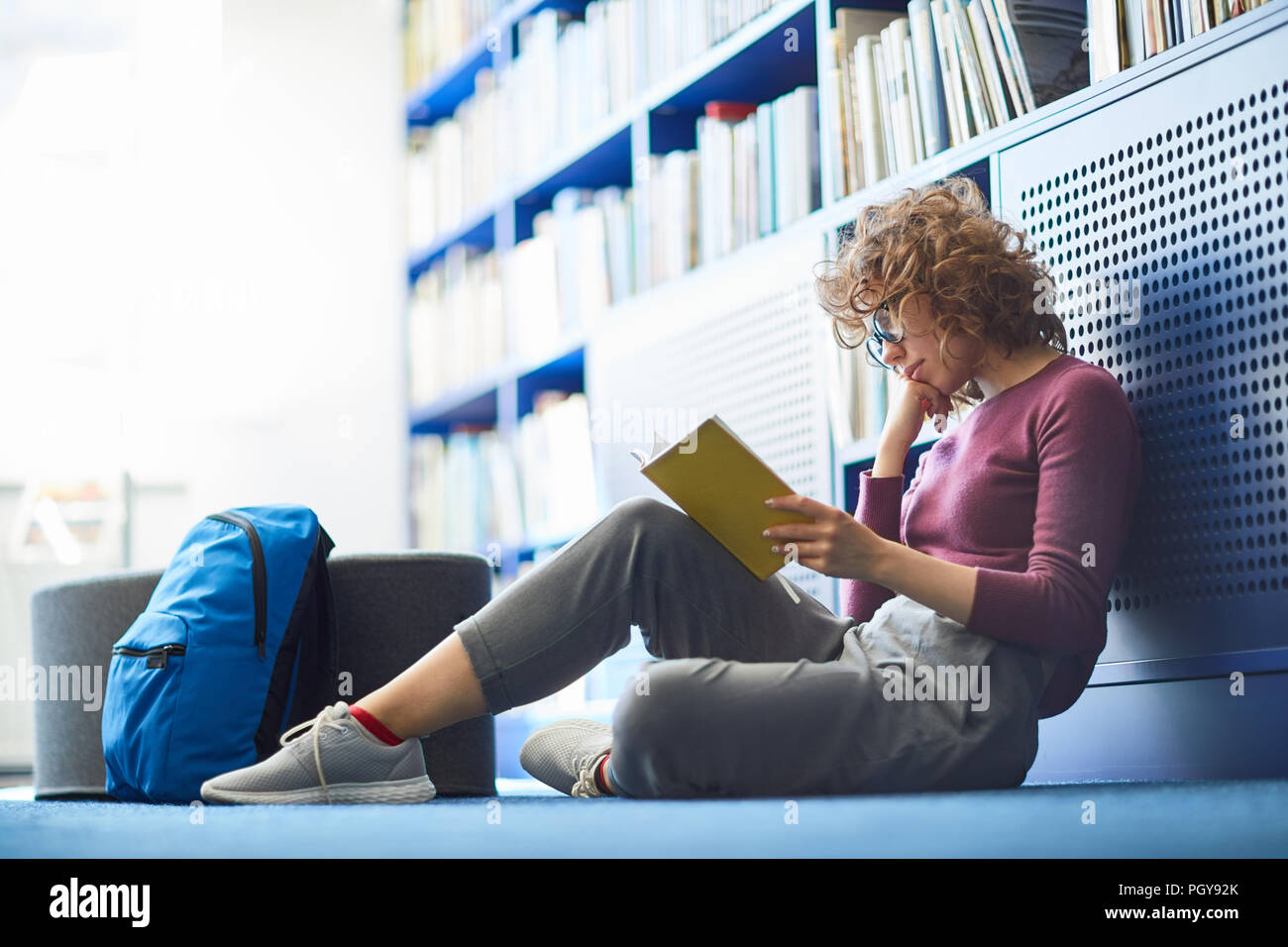 Clever woman student boring reading book on the floor at library Stock ...