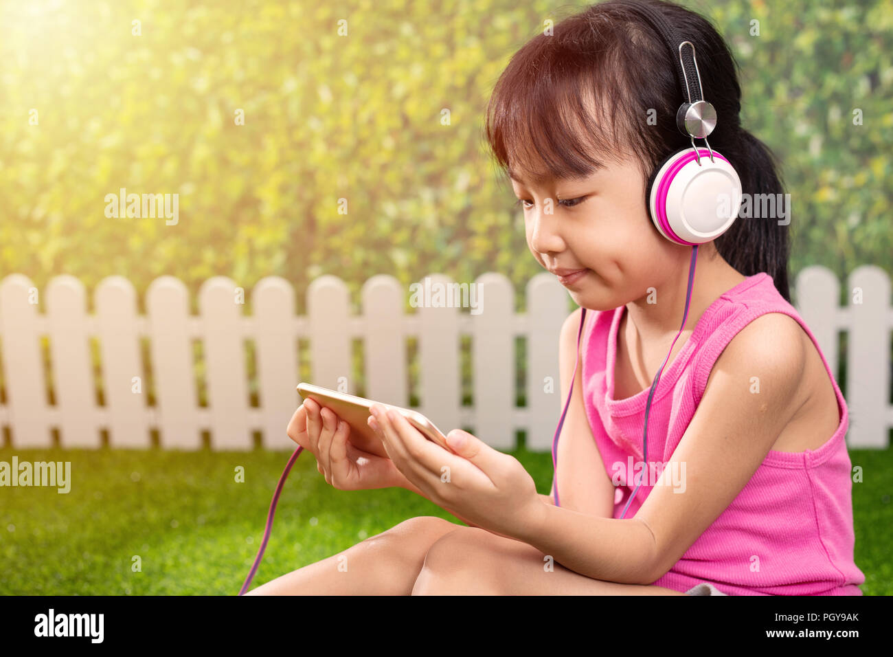 Asian Little Chinese girl playing with mobile phone at outdoor park ...
