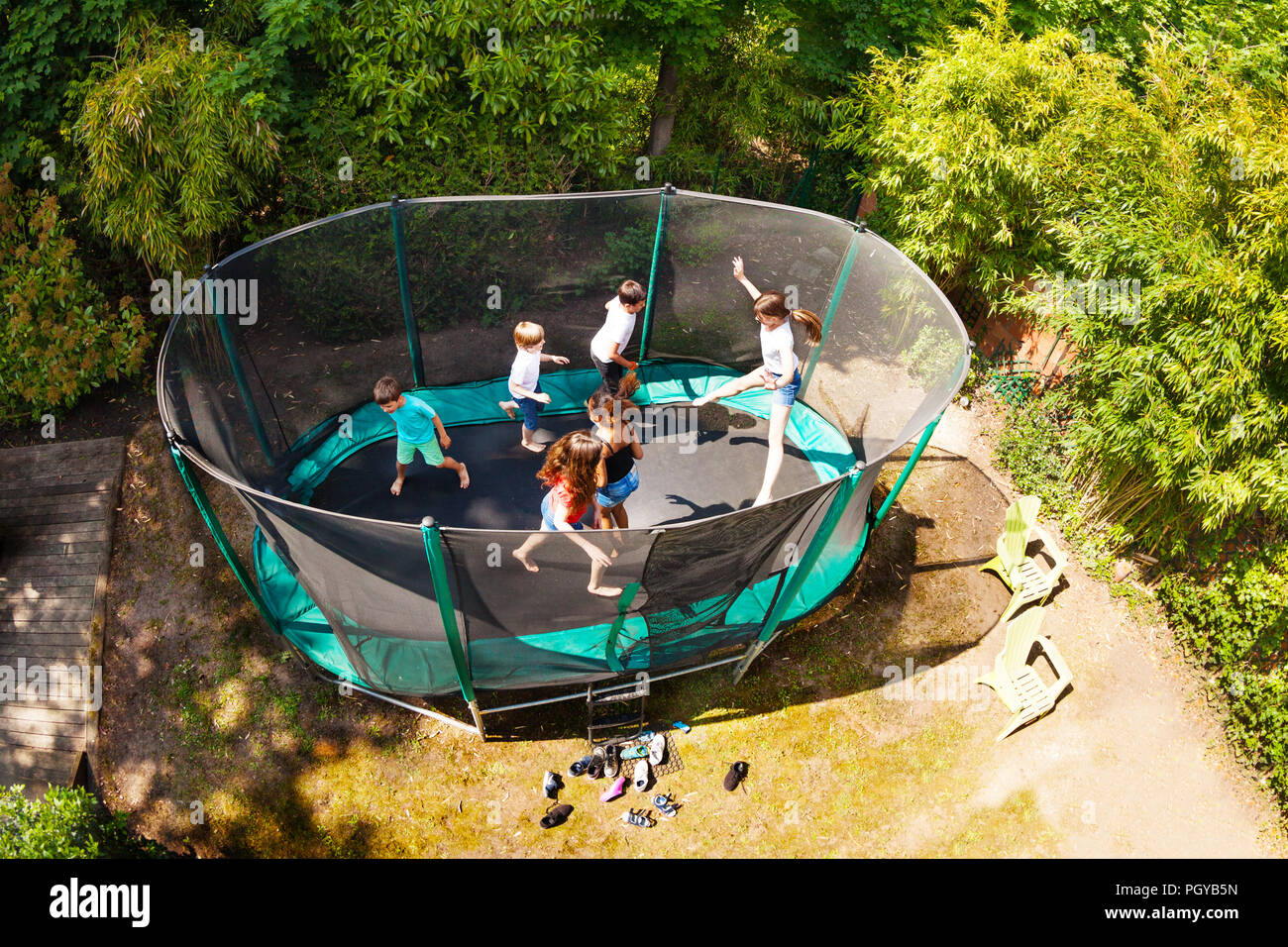 High angle shot of age-diverse boys and girls jumping on the trampoline ...
