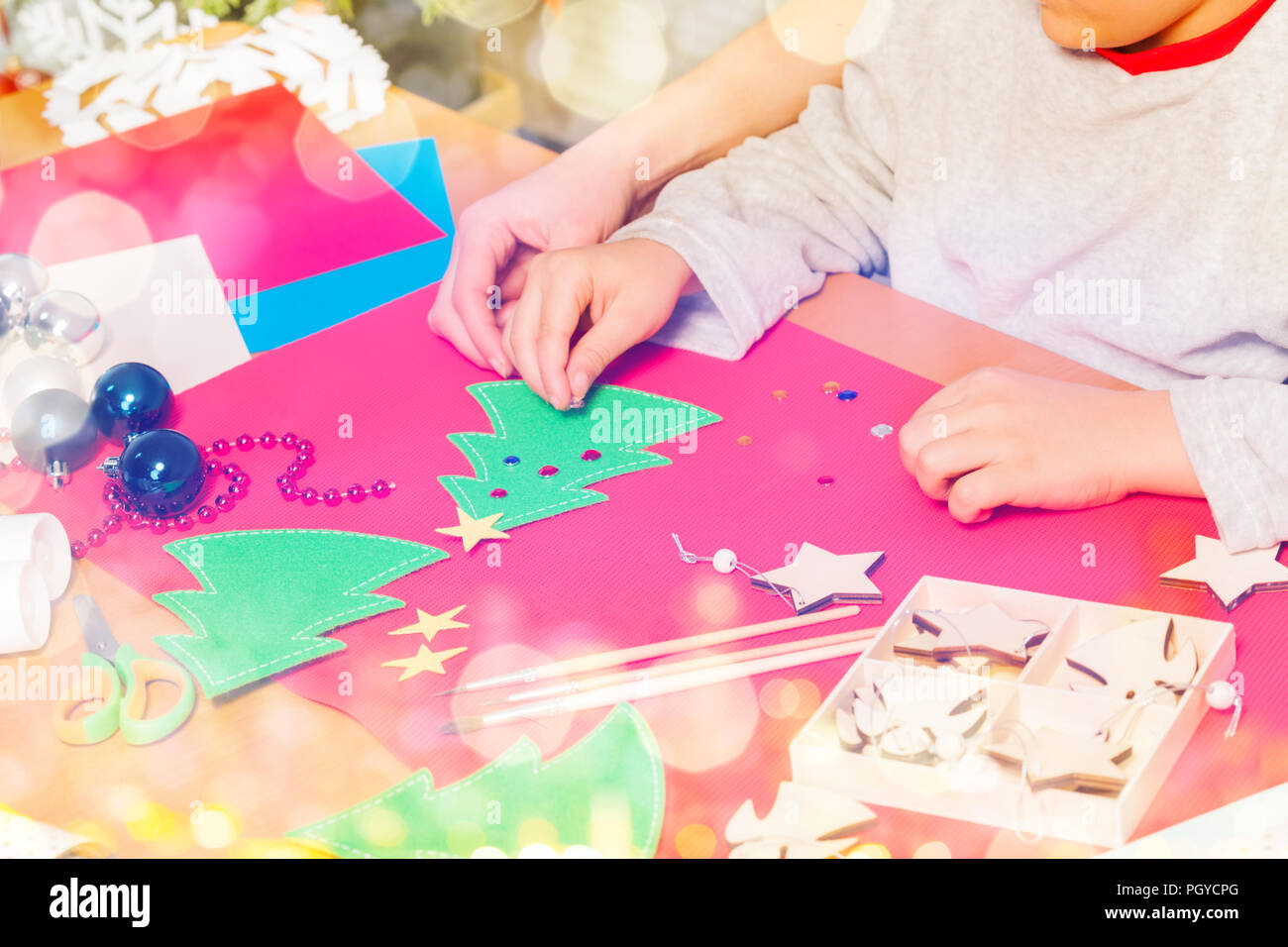 Close-up of kid's hands makes holiday decorations, attaches colorful ...