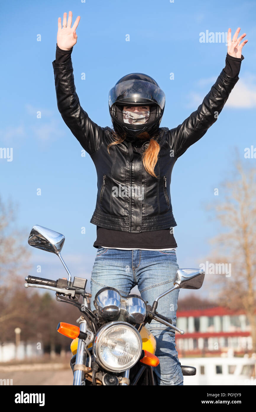 Stunt Caucasian girl balancing while riding motorcycle without arms ...