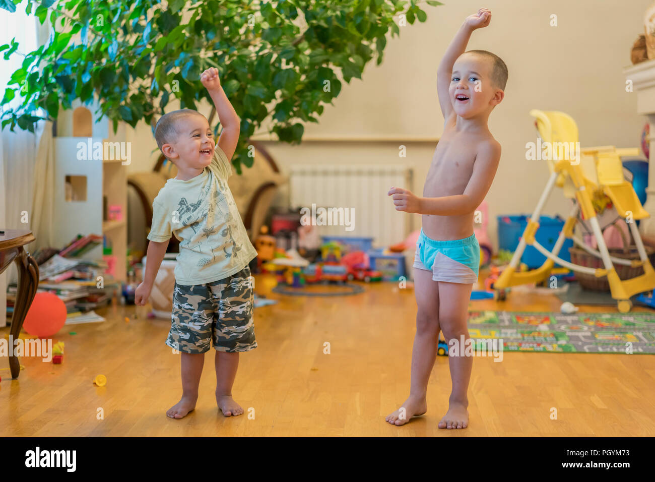 Two little boys are doing exercises. Two small boys at home doing ...