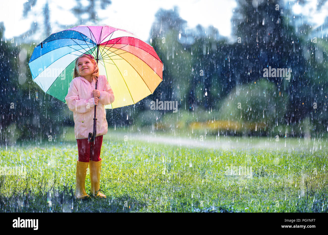 Happy Child With Rainbow Umbrella Under Rain Stock Photo - Alamy