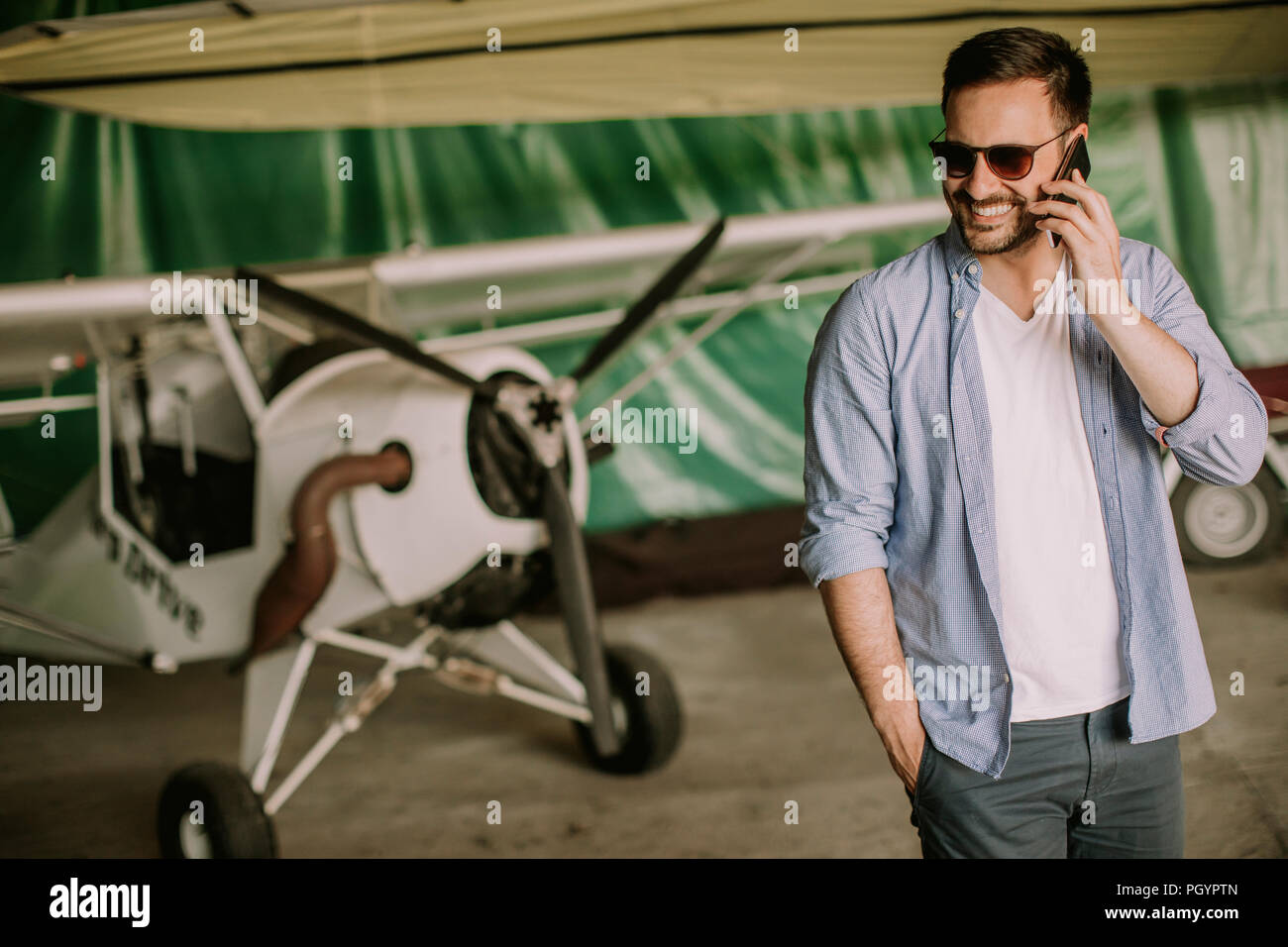 Young handsome young pilot checking airplane in the hangar and using ...
