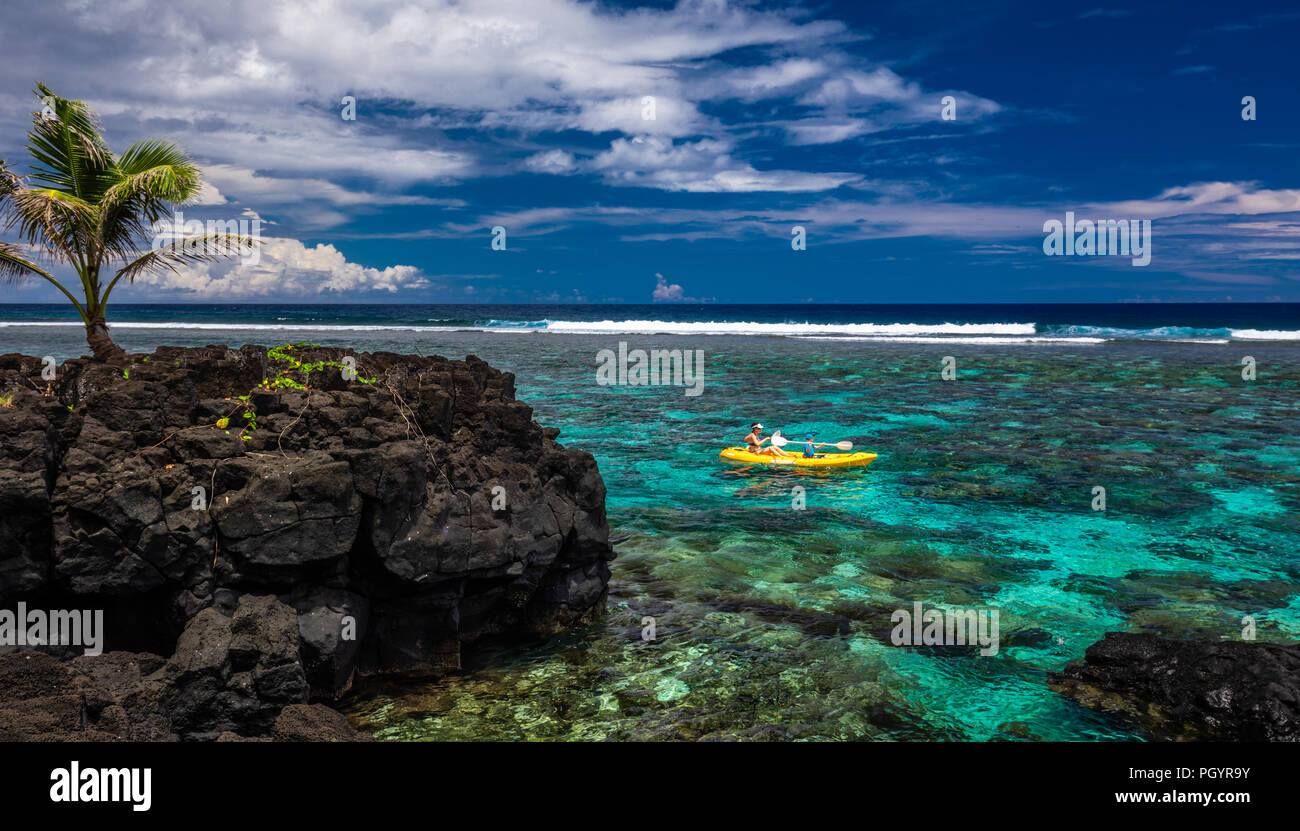 Female and little boy paddling canoe on a lagoon with tropical coral ...