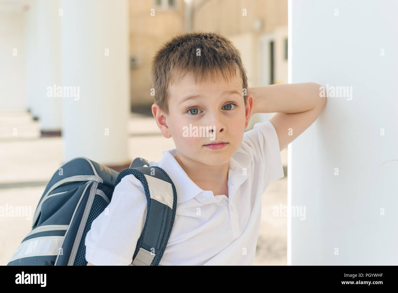 the boy is a first-grader in a white t-shirt with a gray backpack ...