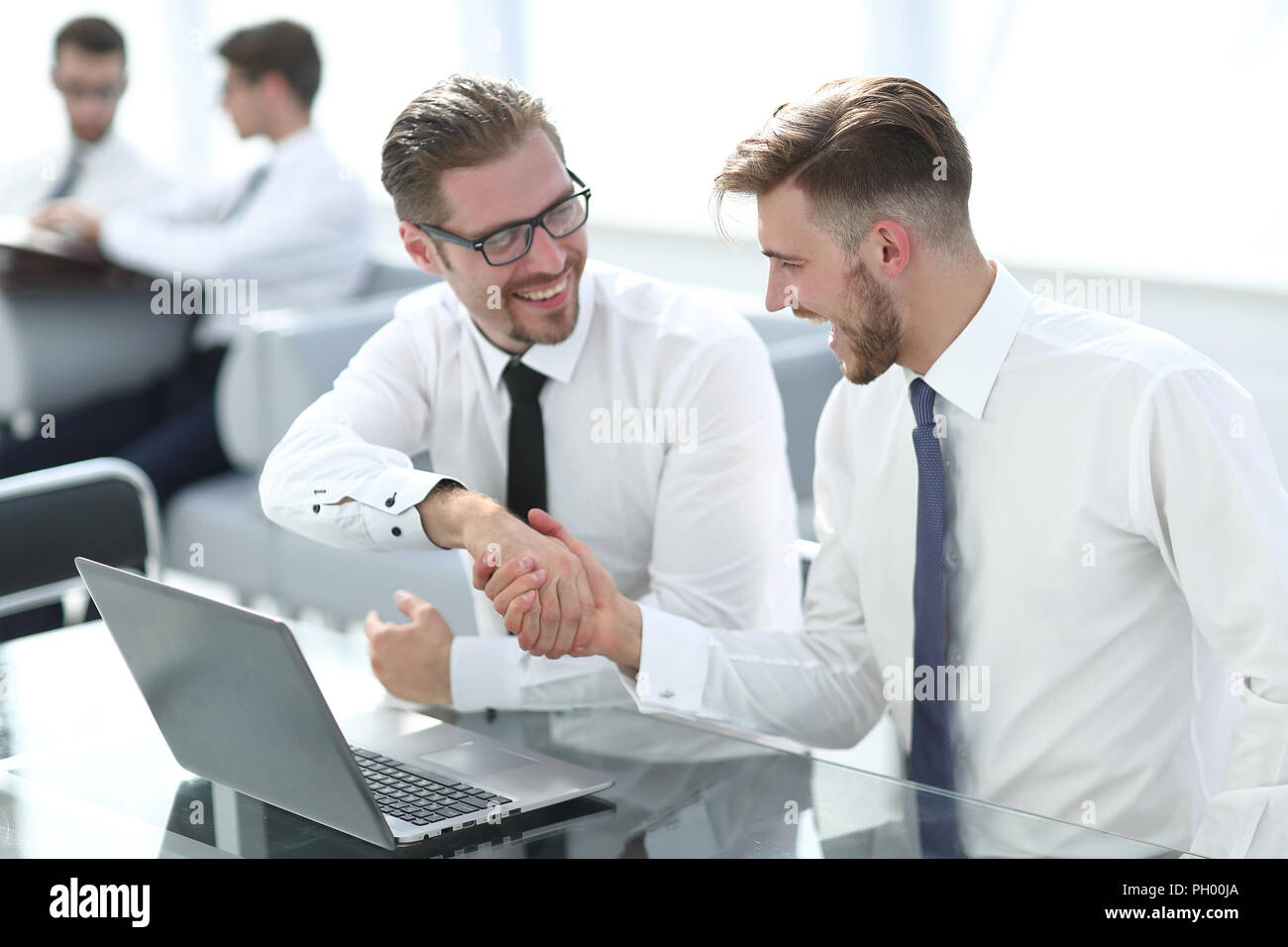 handshake of the employees sitting behind a Desk Stock Photo - Alamy