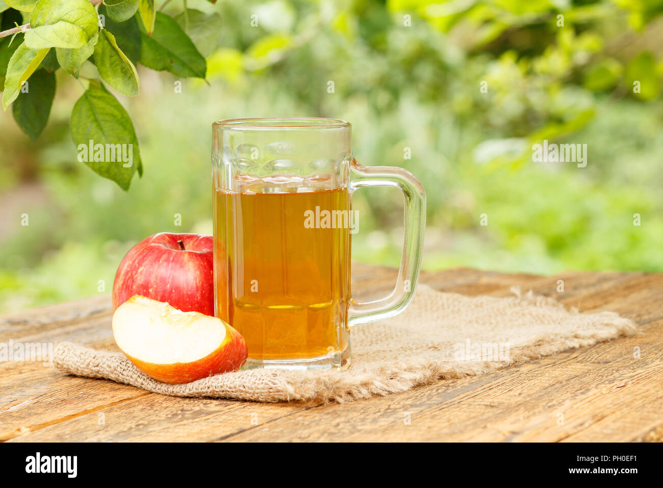 Apple cider in glass goblet and fresh red apples on wooden boards with ...