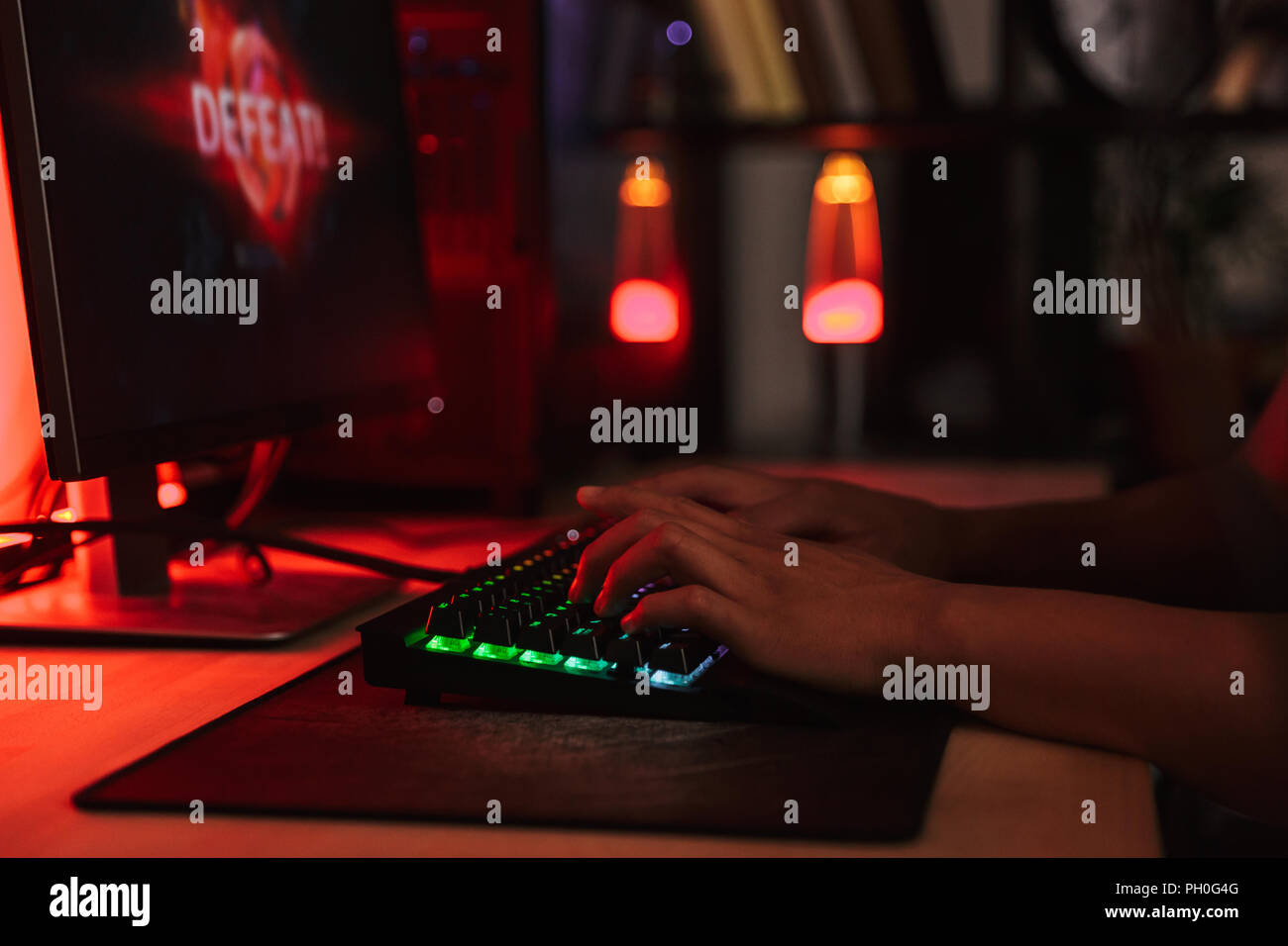 Hands of young gamer man playing video games on computer in dark room ...