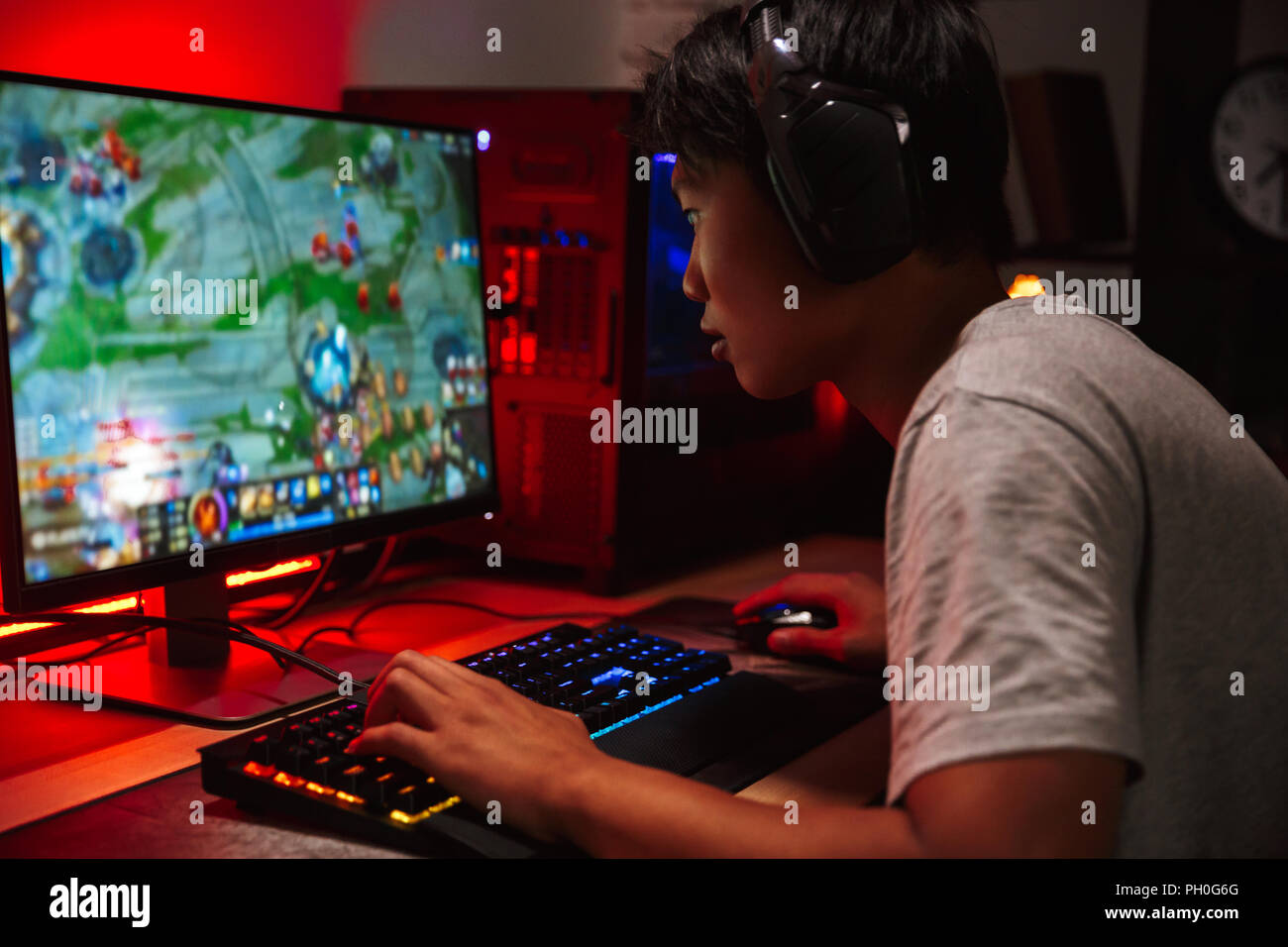 Portrait of asian gamer boy playing video games on computer in dark ...