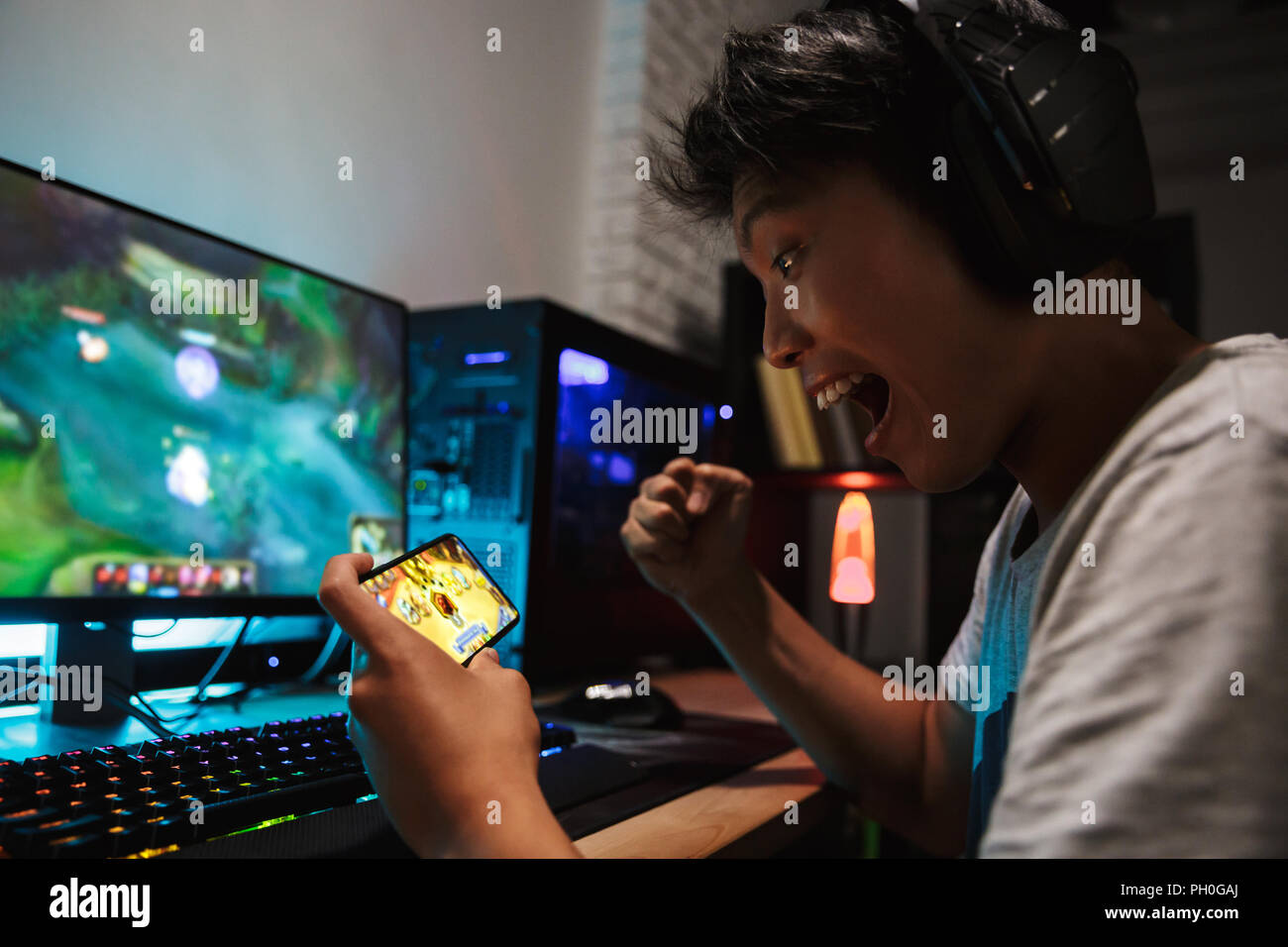 Asian gamer boy screaming while playing video games on smartphone and ...