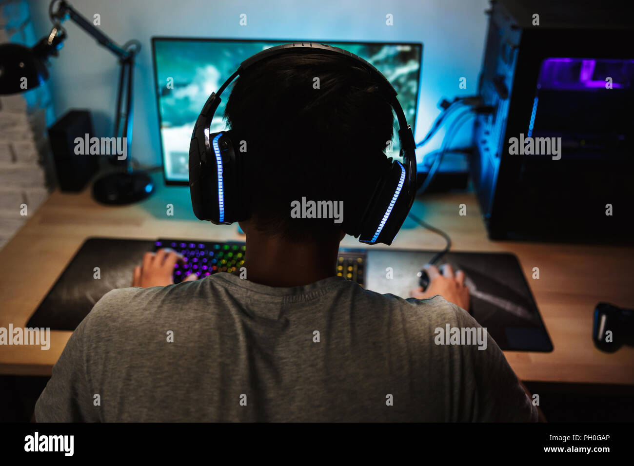 Back view of teenage gamer boy playing video games online on computer ...