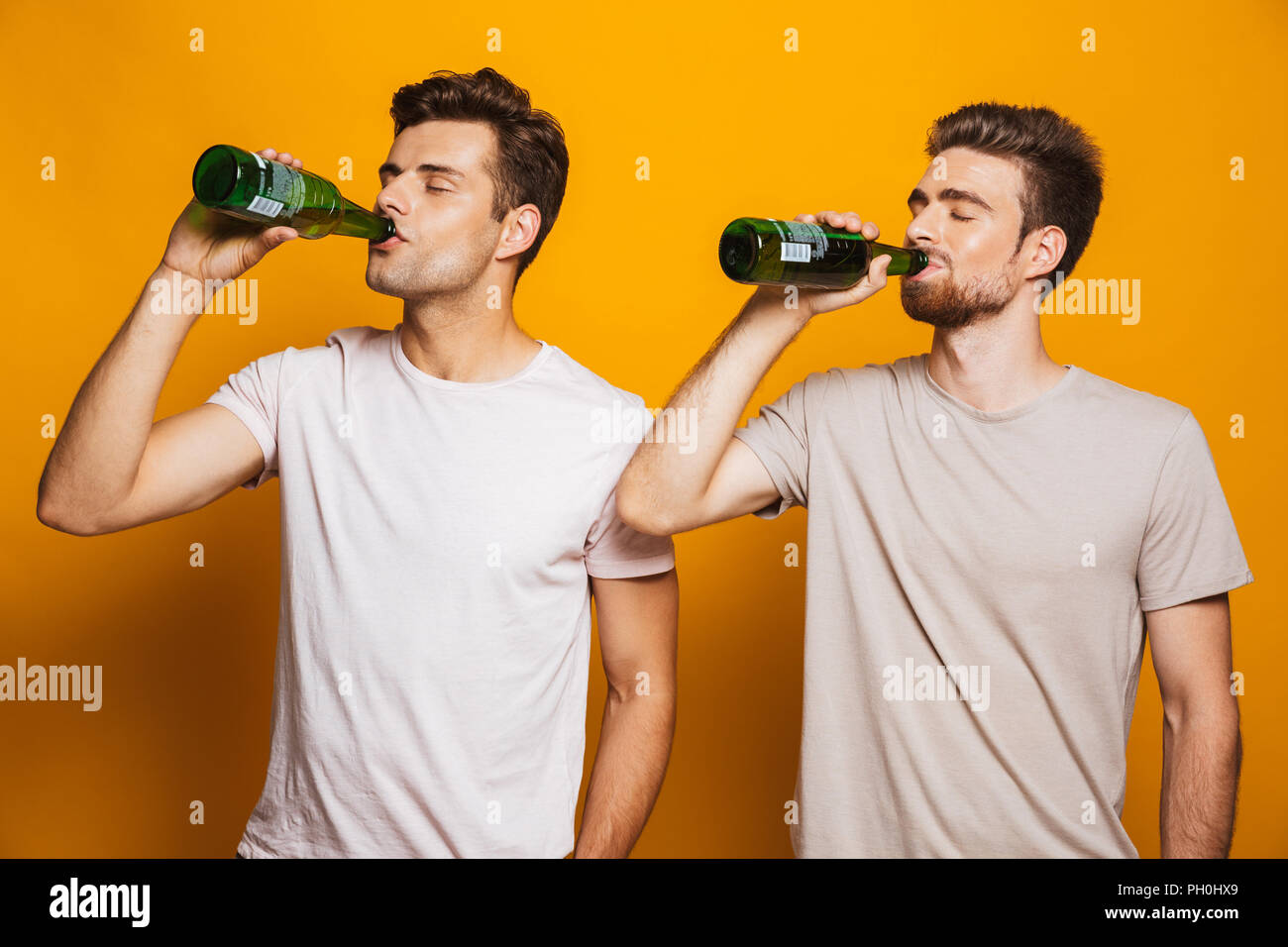 Image of two handsome men friends standing isolated over yellow wall ...