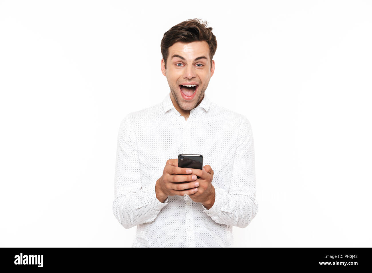 Cheerful guy with short dark hair chatting or typing text message using ...