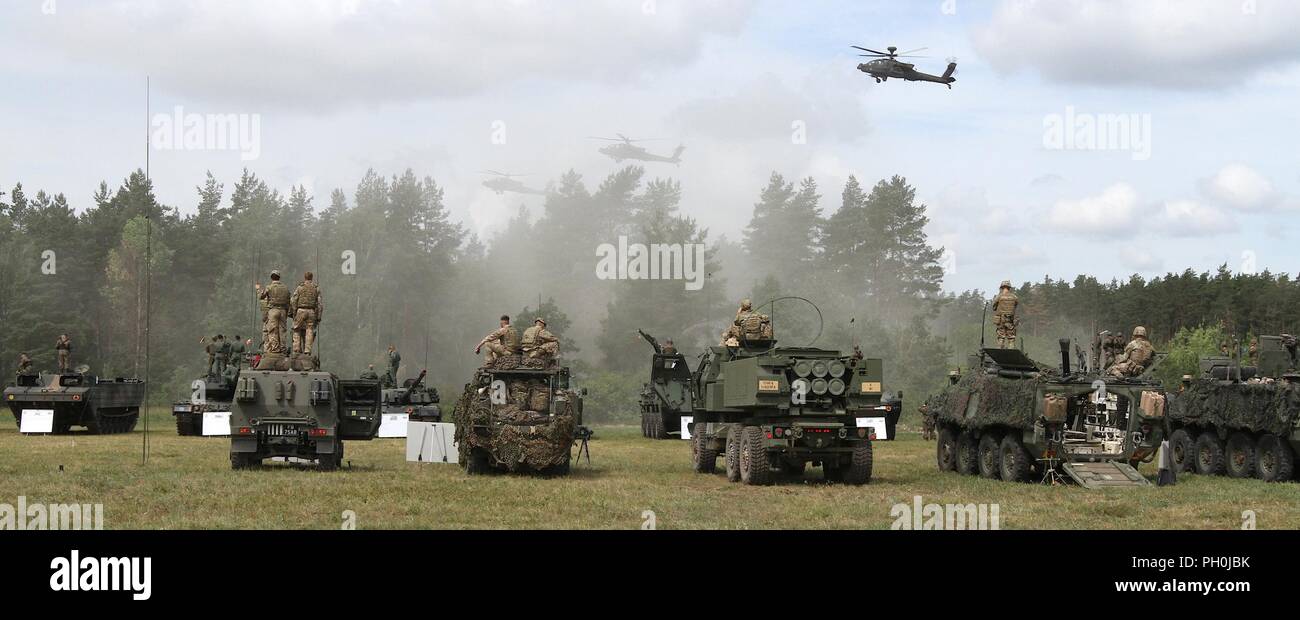 Multinational soldiers sit on top of military vehicles and equipment to ...