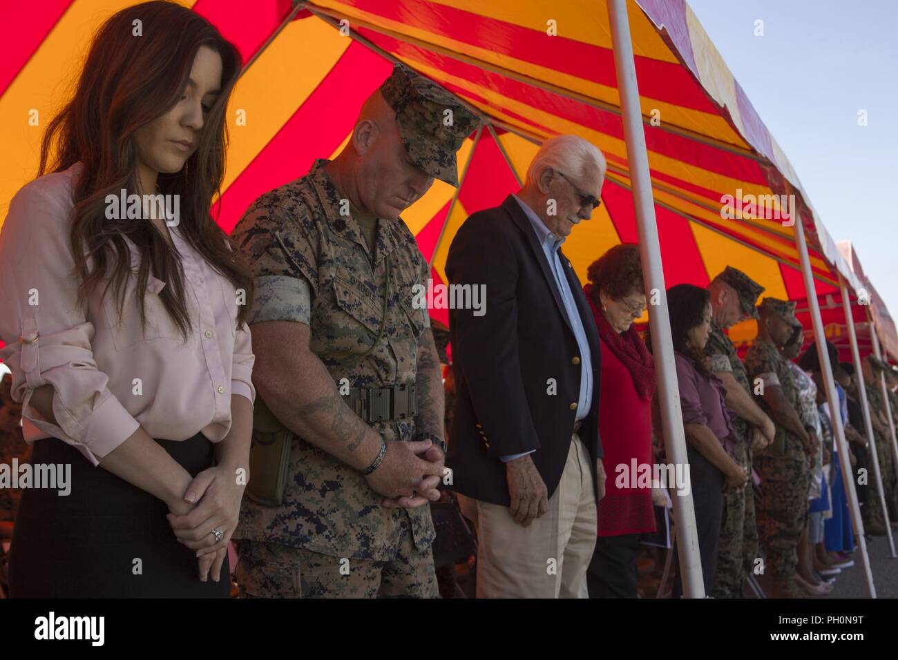 U.S. Marines and civilians bow their heads during the invocation at a ...