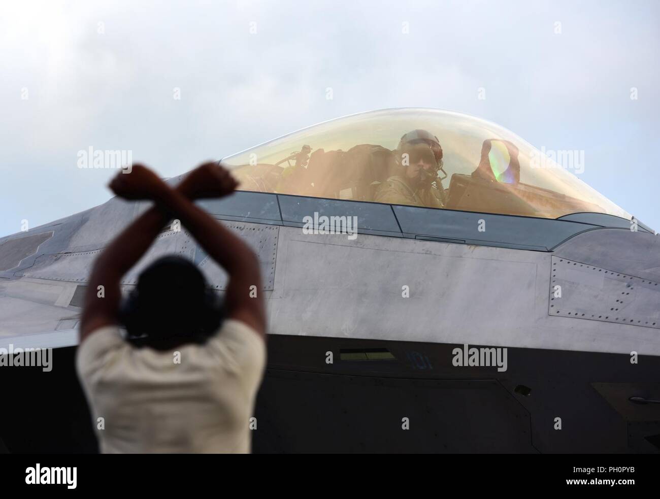 A U.S. Air Force F-22 Raptor pilot is signaled via hand gestures from a ...