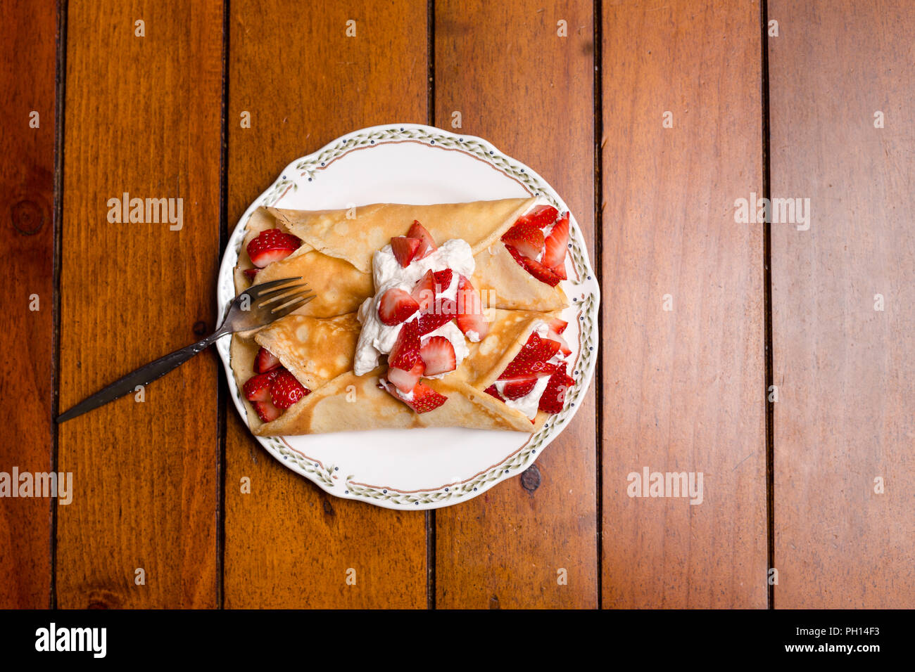 Overhead shot of freshly made golden crepes with strawberries and ...