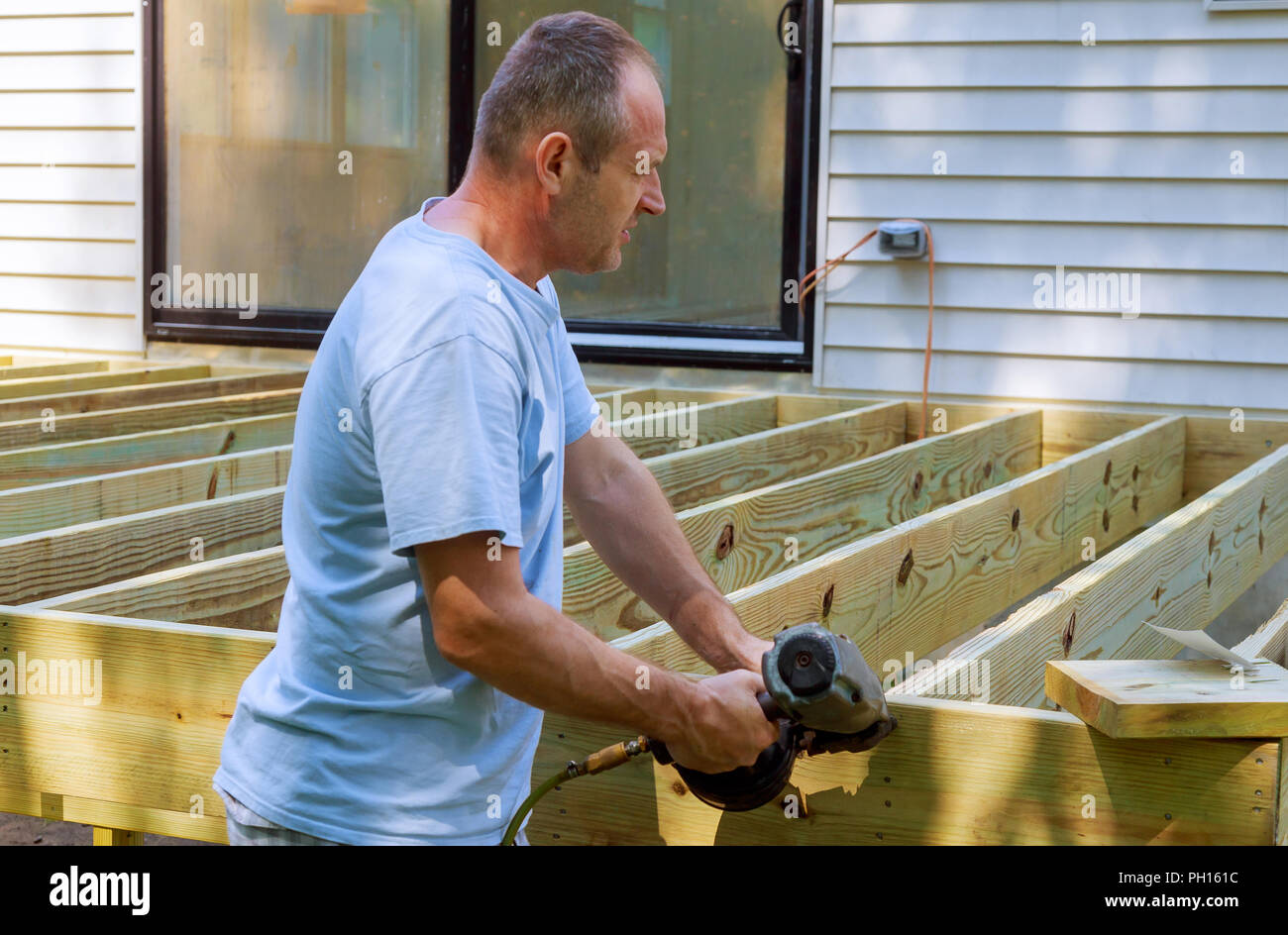 Installing of wooden deck patio carpenter hammering on a deck patio ...