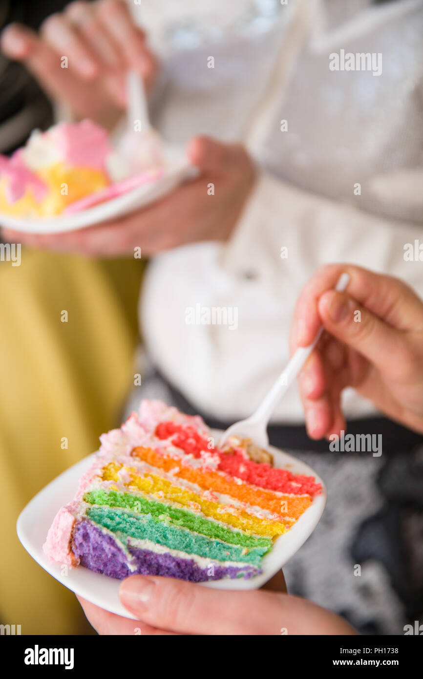 People eating delicious rainbow cake. Homemade colorful cake for ...