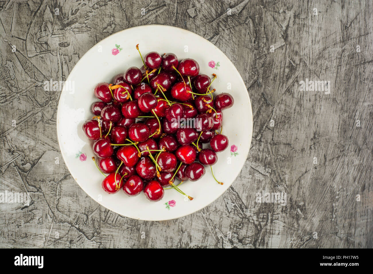 Fresh cherry on plate on concrete background. fresh ripe cherries ...