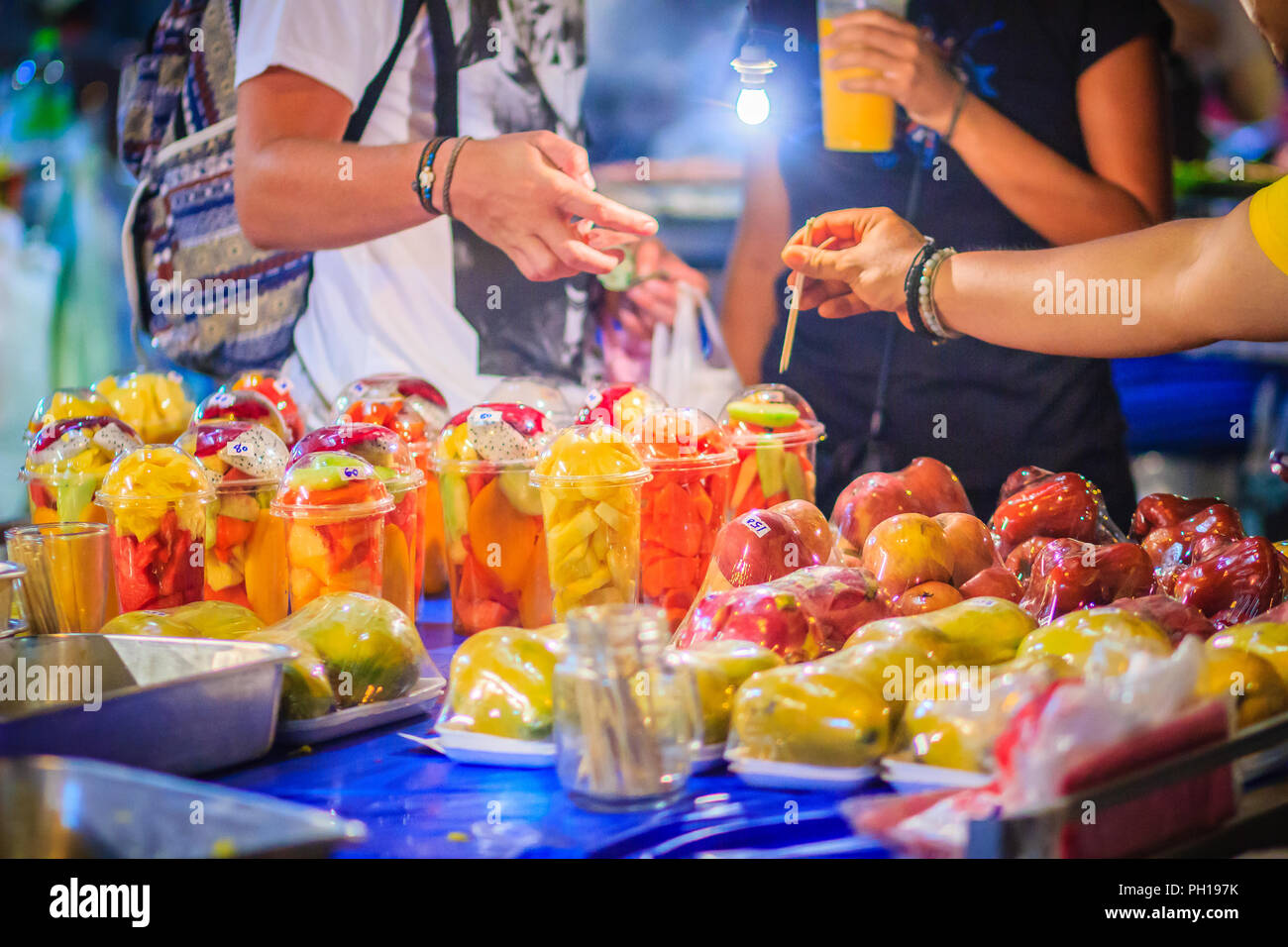 Close up street fruit vendor selling mixed fruits at Khao San Road night market, Bangkok ...
