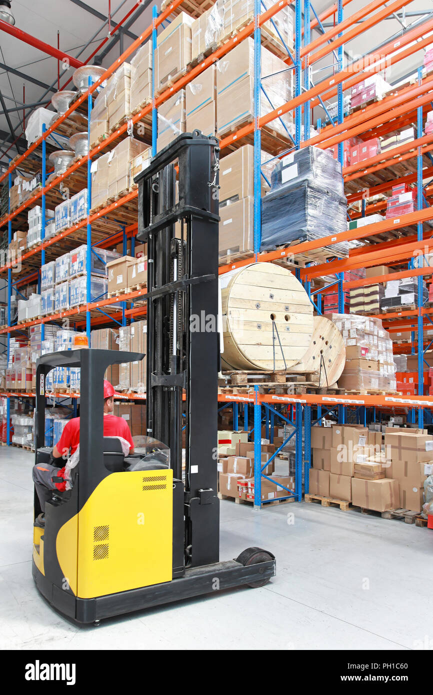 Forklift loading roll pallet in distribution warehouse Stock Photo - Alamy