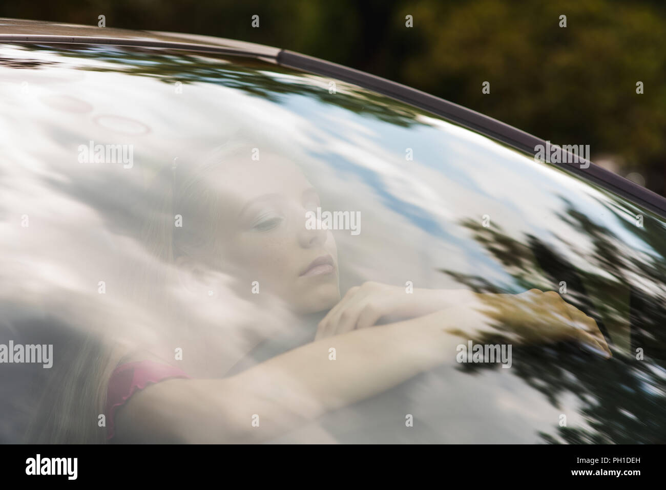 Reflections on glass and female behind in vehicle. Girl face though car ...