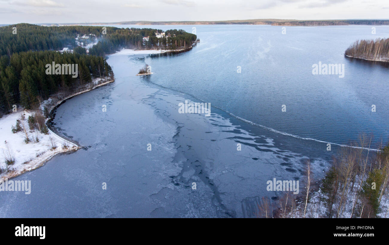 Aerial view of partially frozen lake and forest on cold winter day ...
