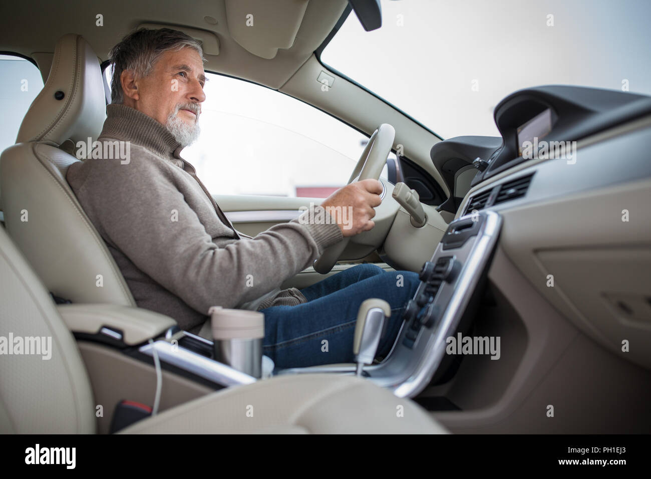 Senior man driving his modern car, going in reverse, watching out not ...