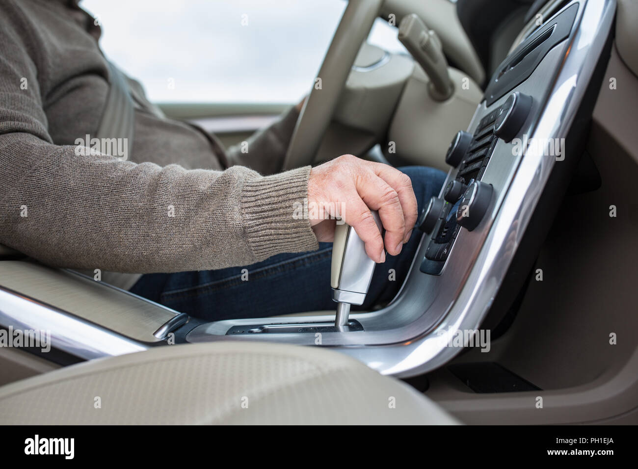 Senior man driving his modern car, going in reverse, watching out not ...