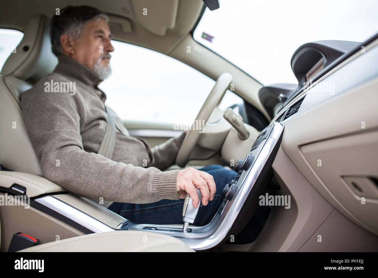 Senior man driving his modern car, going in reverse, watching out not ...