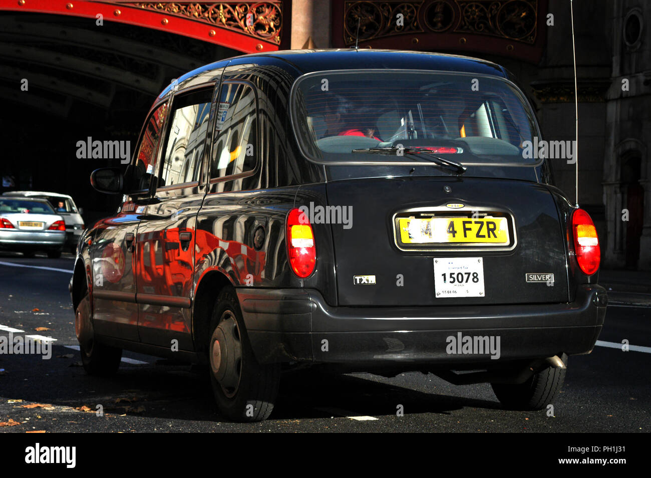 The back view of a Black cab moving on a street in the City area of ...