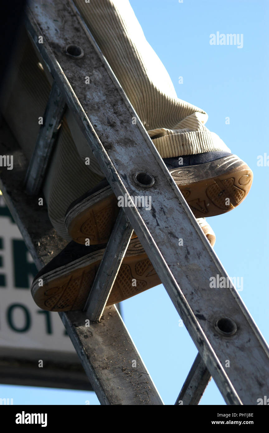 Mans feet and legs going up ladder rungs in the City area of London ...